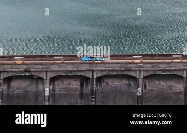 Aerial View Of Two Cars Driving On A Bridge Over A Large Body Of Water