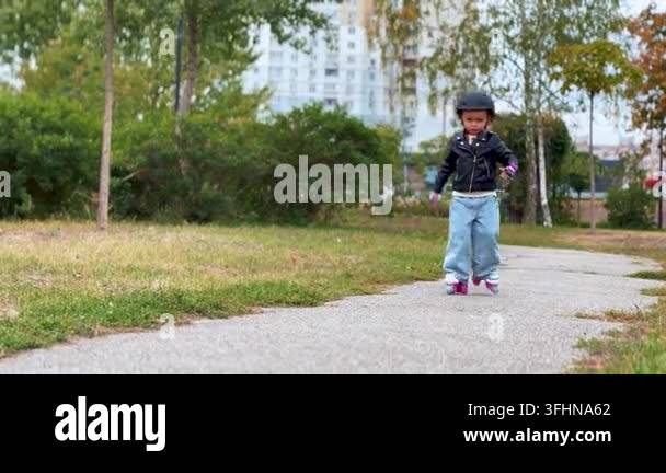 Young child wearing a helmet and protective wrist guards rides colorful ...