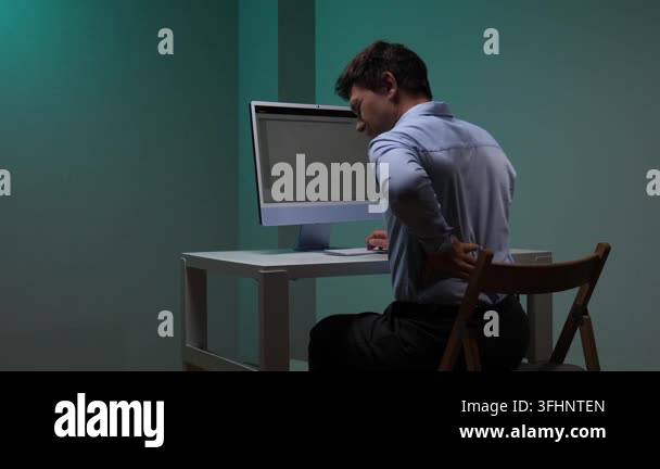 Man sitting at office desk clutching lower back in pain after long ...