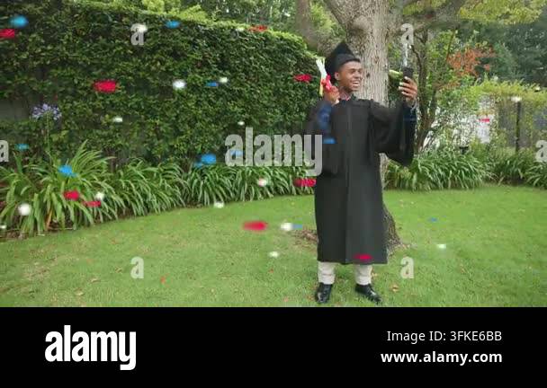 Grad raising phone and showing diploma in garden as falling confetti ...