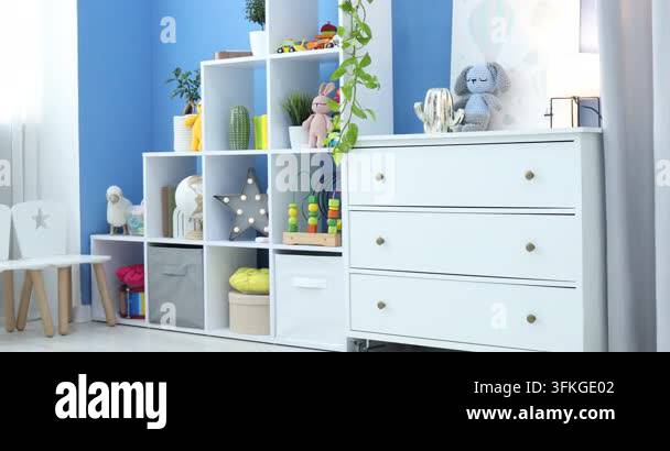Shelving unit with different toys and decor near blue wall in child's ...