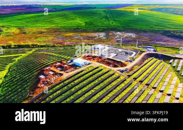 Solar substation stands amid rows of panels. Overhead shot captures ...
