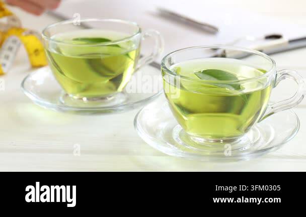 Cups of weight loss tea on white wooden table. Woman with measuring ...