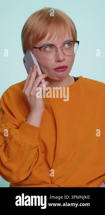 Tired sleepy young woman in glasses talking on mobile phone with friend ...