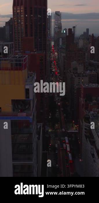 Vertical video: Fly between high rise buildings in city at twilight ...