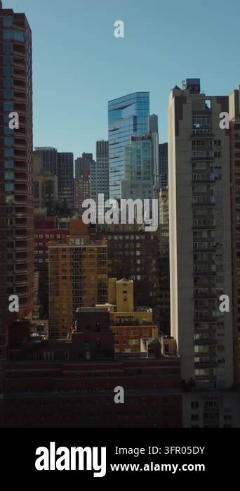 Vertical video: Forwards fly between high rise apartment buildings ...