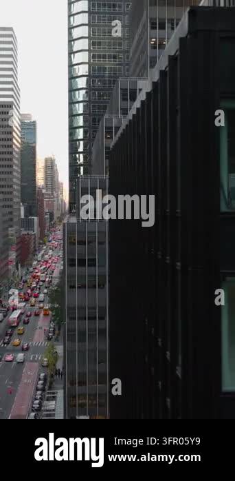 Vertical video: Sliding reveal of wide and busy avenue between modern ...