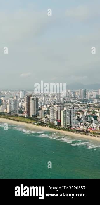 High-angle view of dense high-rise buildings beside a sandy shoreline ...