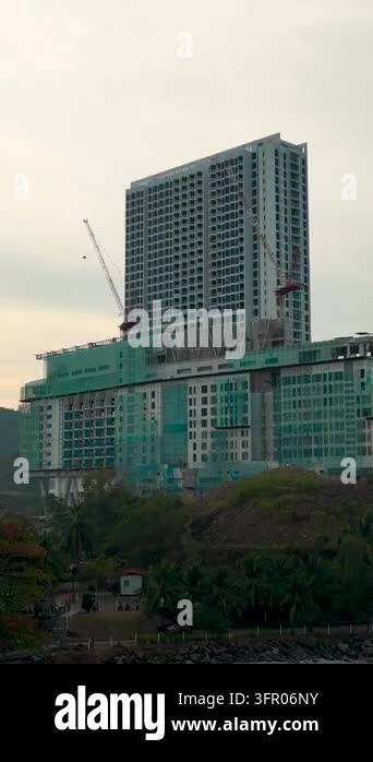 High-rise building under construction with cranes, green safety netting ...