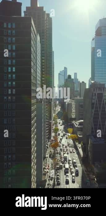 Vertical video: Forwards fly above street crossing and between modern ...