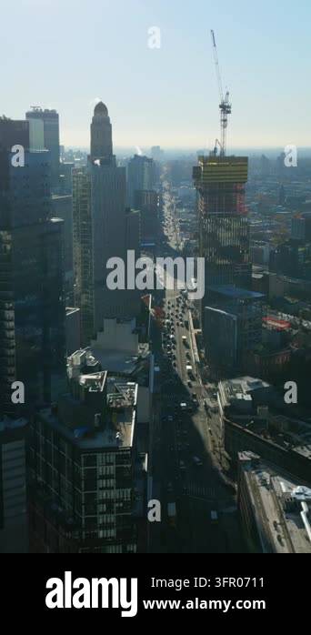 Vertical video: Forwards fly high above busy street surrounded by ...