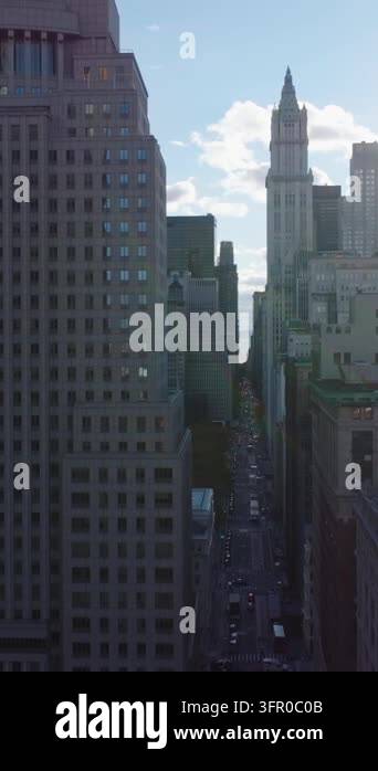 Vertical video: Fly between high rise buildings against sunshine ...