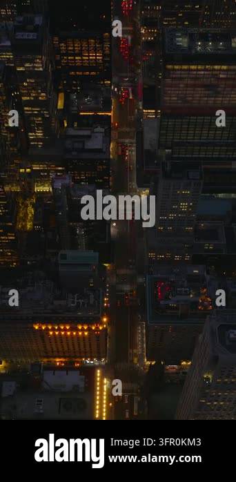 Vertical video: High angle view of evening city. Tilt down on lighted ...