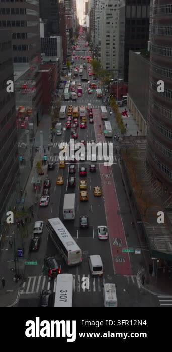 Vertical video: Forwards fly above busy avenue. Wide one way road ...