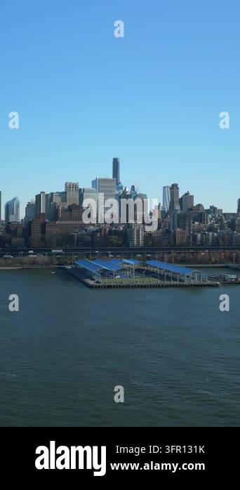 Vertical video: East river with piers and downtown high rise office and ...