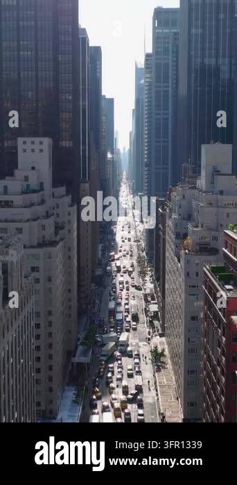 Vertical video: Forwards fly above busy avenue between modern high rise ...
