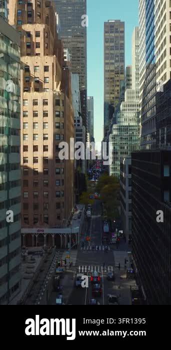 Vertical video: Forwards fly above street between modern high rise ...
