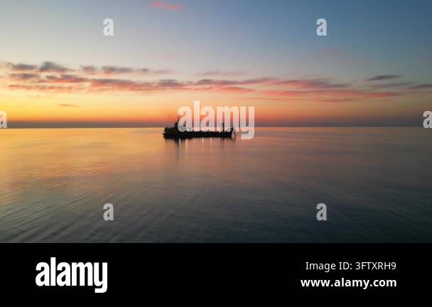Aerial drone footage of a large cargo ship sailing on calm water during ...
