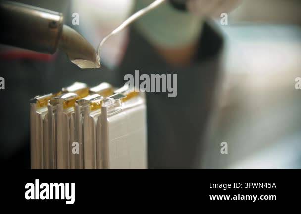 Close-up of a worker soldering contacts on a modern lithium-ion battery ...