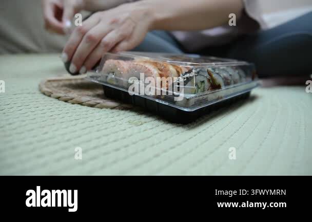 Extreme close-up of fresh sushi rolls in sharp focus with a woman ...