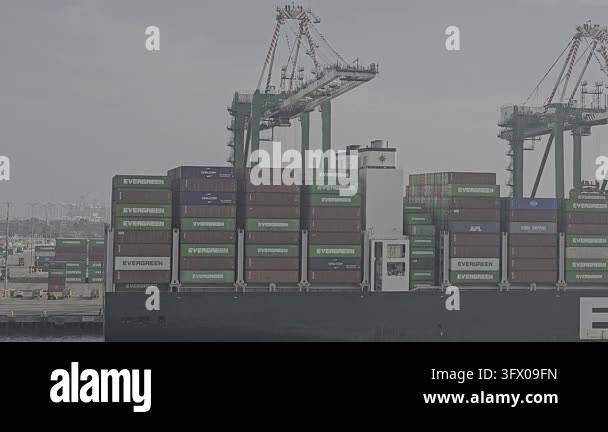 Cargo ship loaded with shipping containers at port under a cloudy sky ...