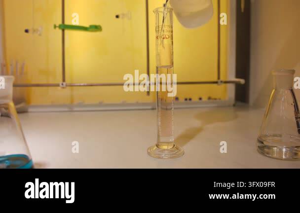 Close eye-level laboratory view as hand pours clear liquid from beaker ...