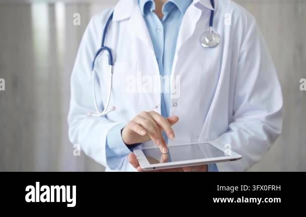 Doctor woman wearing lab coat and stethoscope using tablet computer in ...