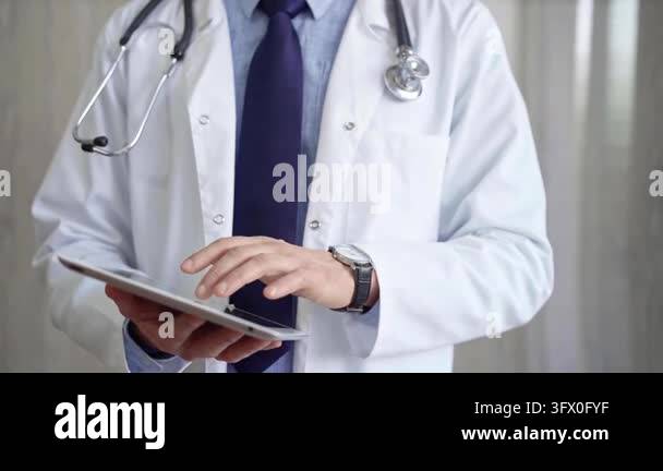 Doctor man wearing lab coat and stethoscope using tablet computer in ...
