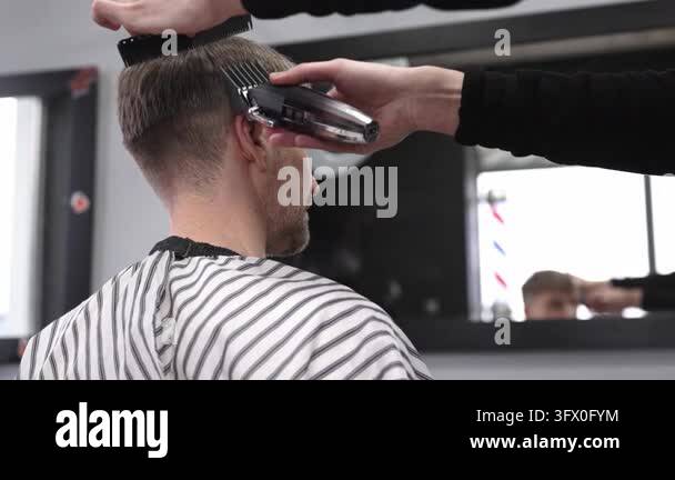 Professional barber skillfully cutting hair of male client with ...