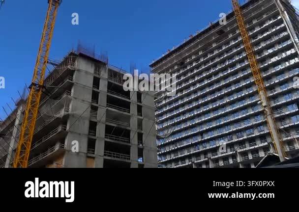 Camera tilts upward between tower cranes and unfinished buildings in ...