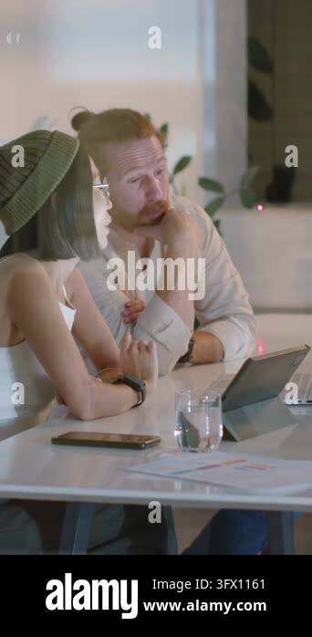 Vertical video: Team leaning over tablet, passerby sparking UI icons ...