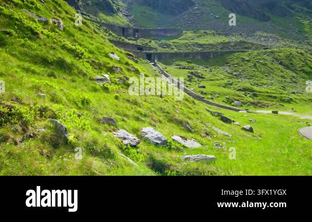 Wide framing presents Transfagarasan curves crossing green Balea Valley ...
