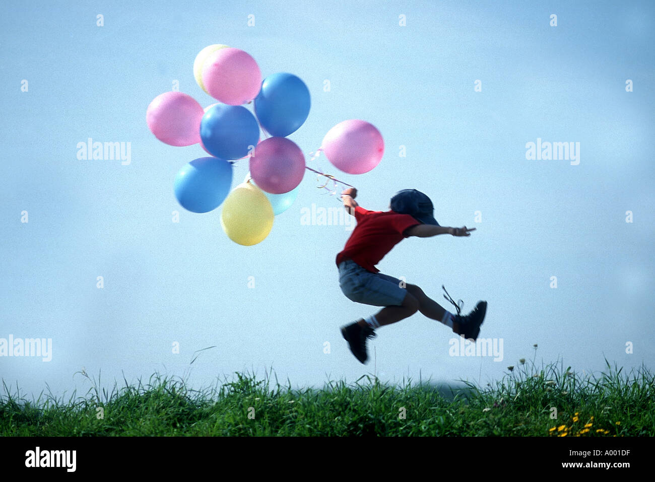boy jumping with balloons open air sky is blue Stock Photo - Alamy