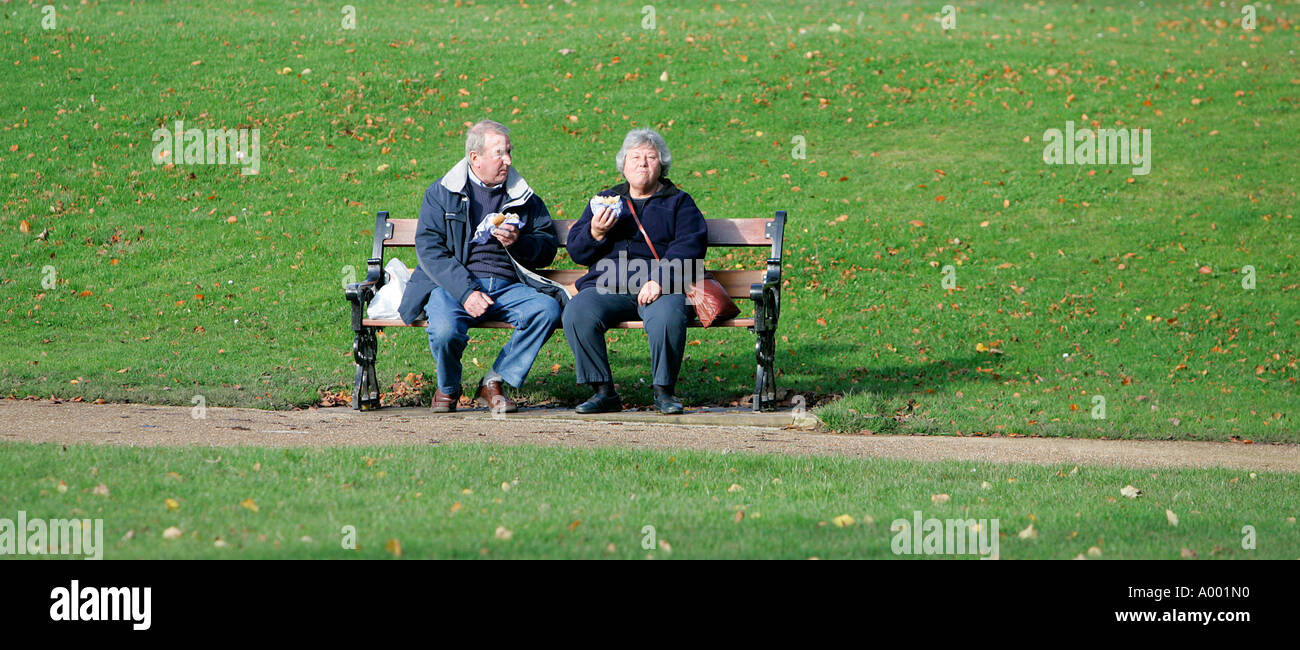 couple two persons sitting on a bench eating in Buxton North England UK ...