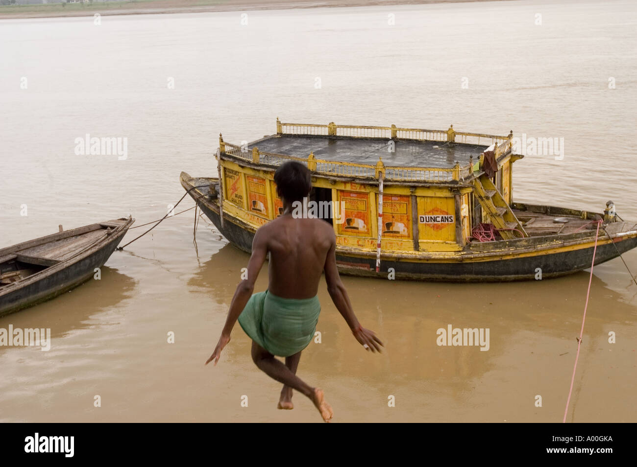 Indian boy jumping from ghat into Ganges or Ganga river and looking ...