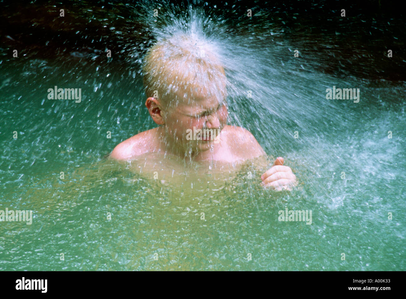 young western male tourist standing under a powerful cascade of water ...
