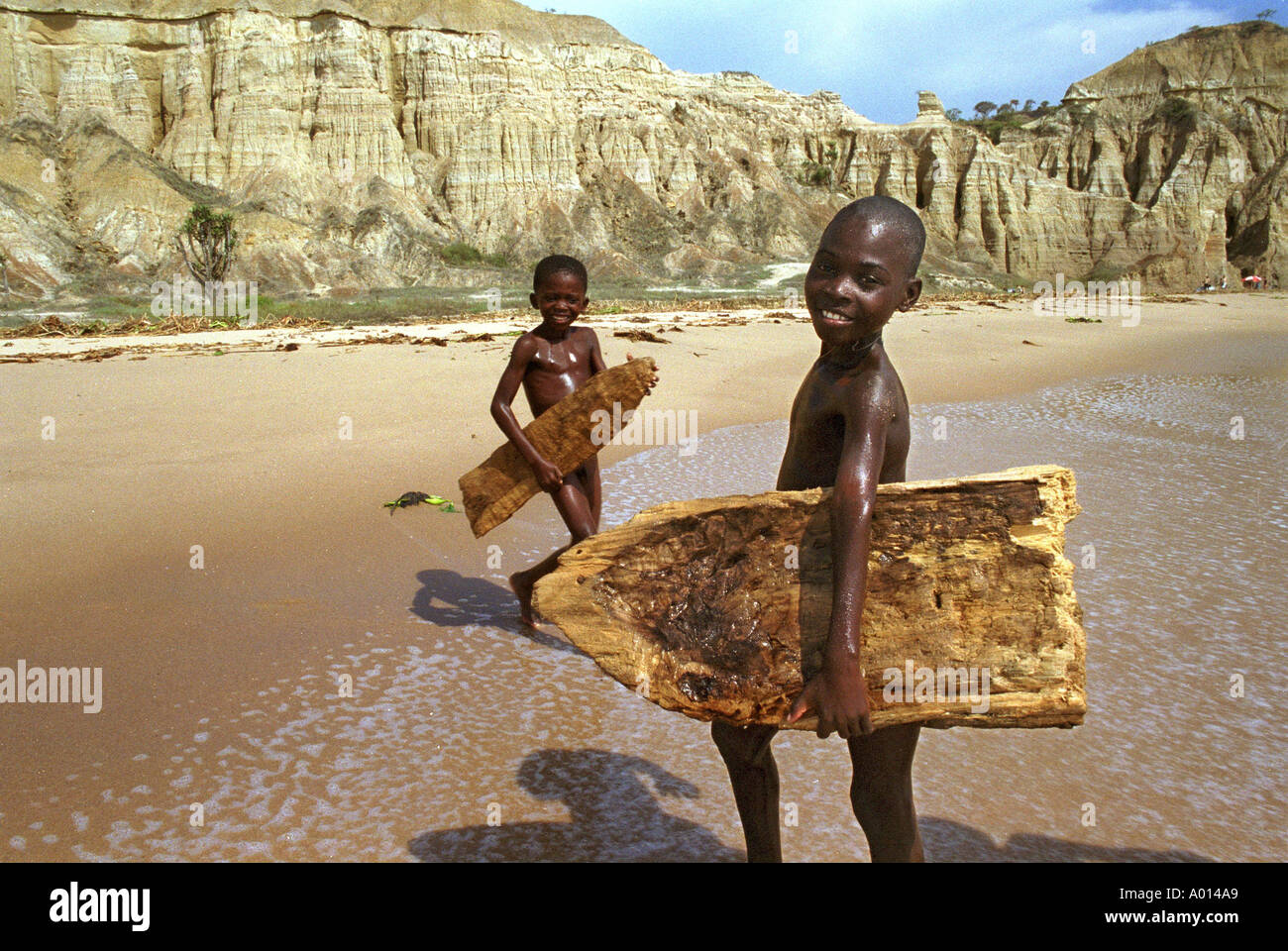Angolan children practice surfing on their hand made boards on a beach ...