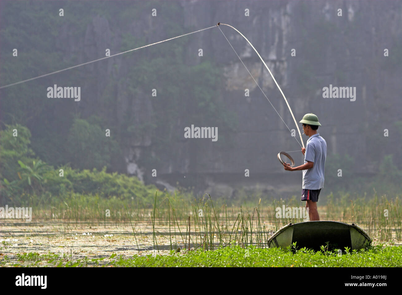 Vietnamese fisherman with rod and hand reel Ngo Dong River Tam Coc near ...
