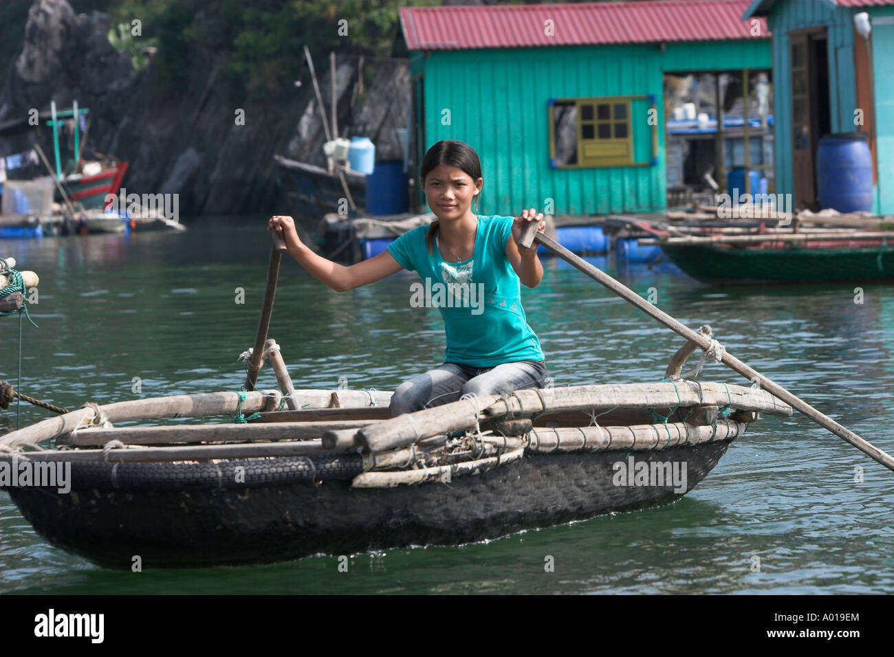 Conical hat woman rows traditional woven boat around floating fishing ...