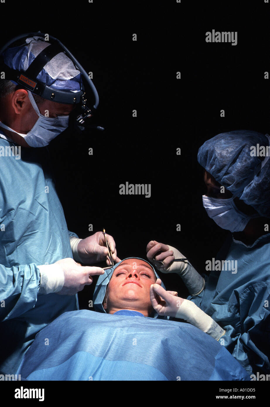 Medical doctor and nurse performing plastic surgery on female patient ...