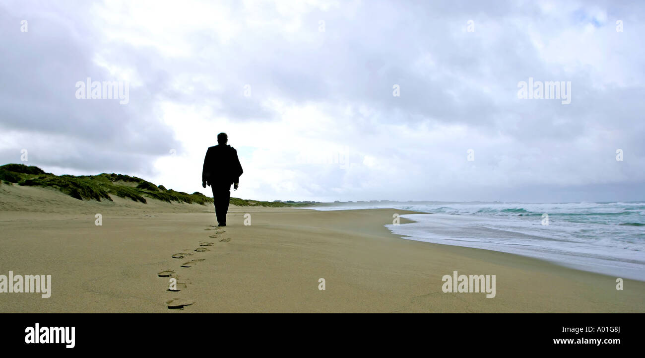 Single man walking on deserted beach Stock Photo - Alamy