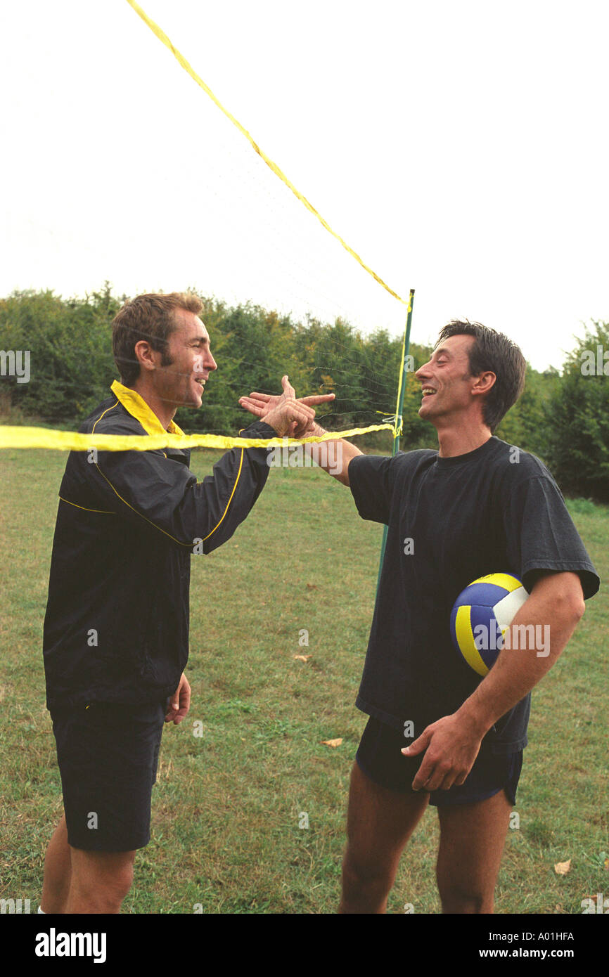 Two men arguing playfully through a volleyball net Stock Photo - Alamy