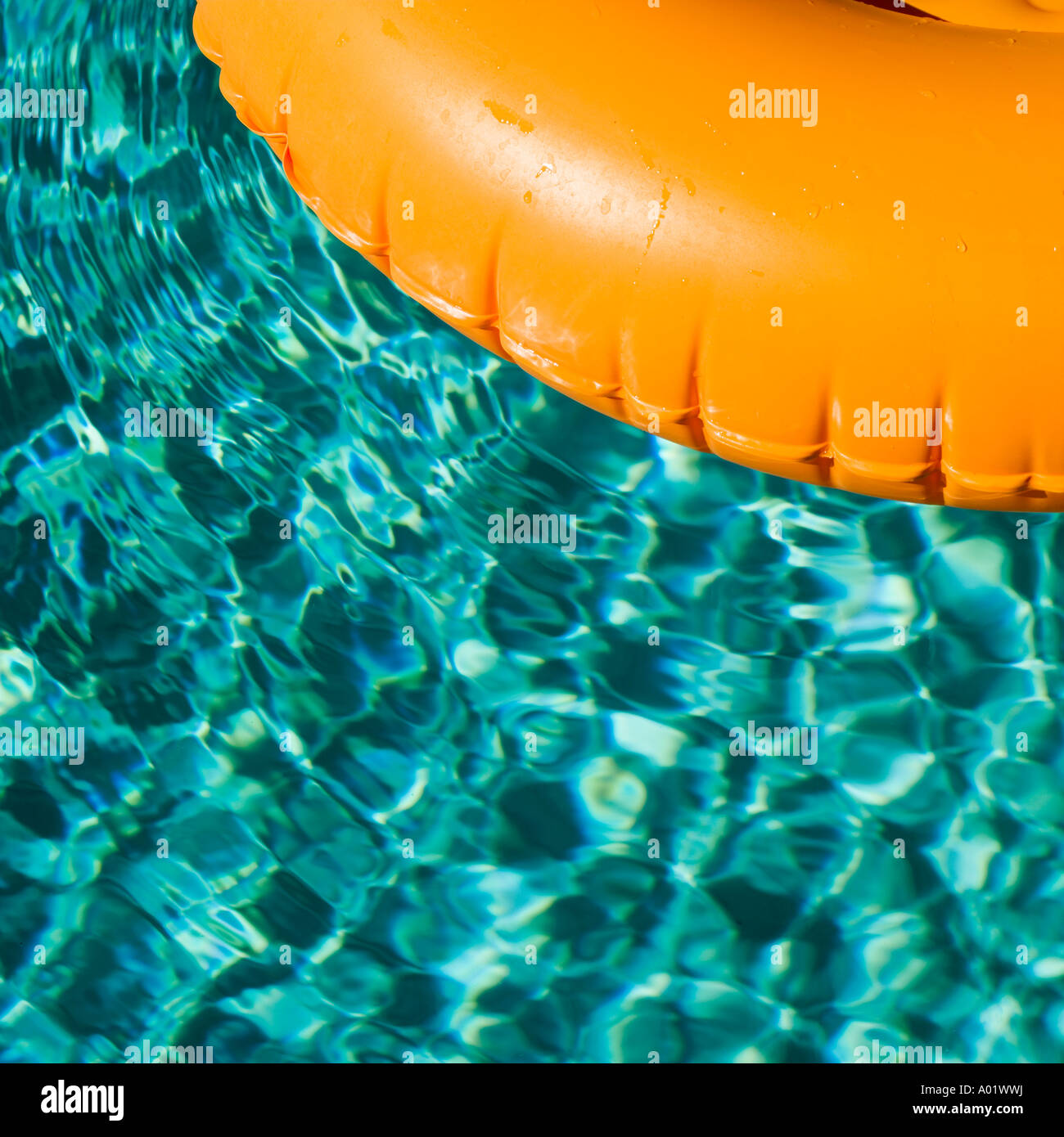 Orange inflatable ring floats in a blue swimming pool casting a shadow ...