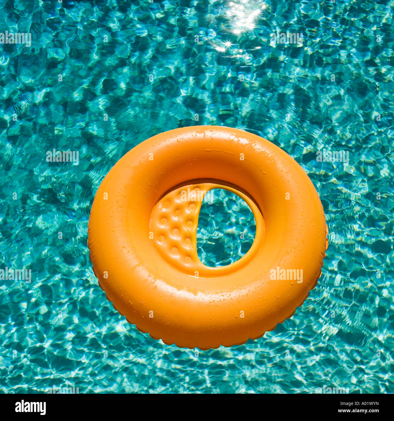 Orange inflatable ring floats in a blue swimming pool casting a shadow ...