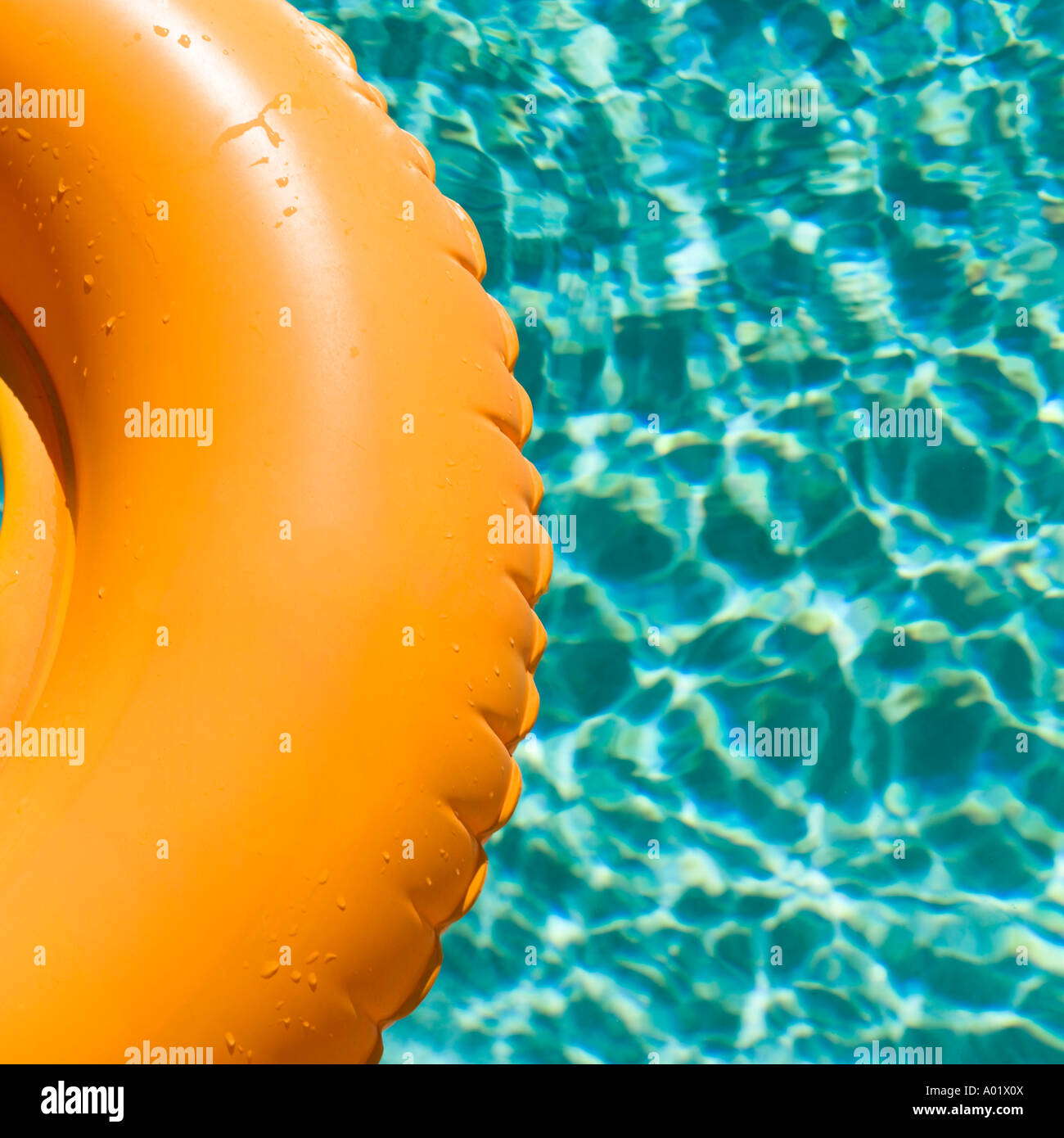 Orange inflatable ring floats in a blue swimming pool casting a shadow ...