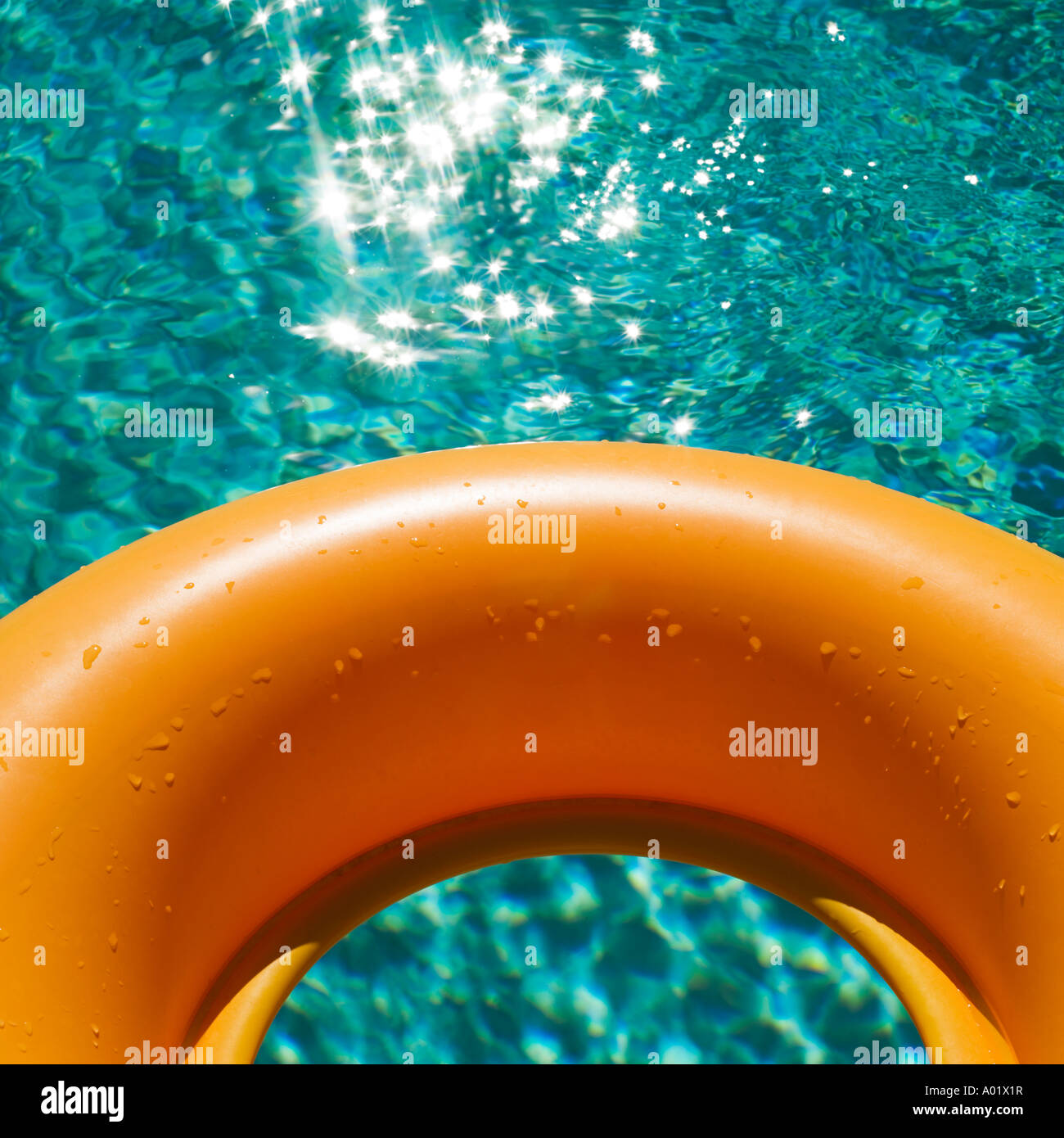 Orange inflatable ring floats in a blue swimming pool casting a shadow ...