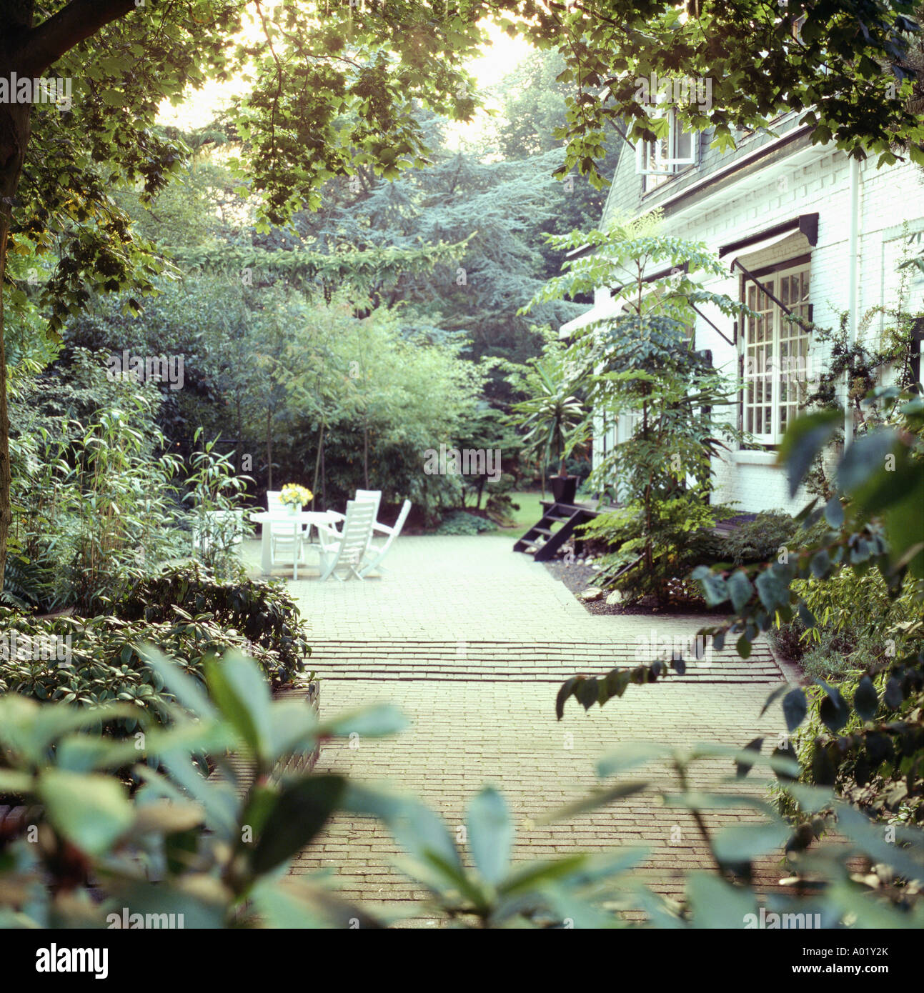 Large paved terrace with white chairs and table in front of traditional ...