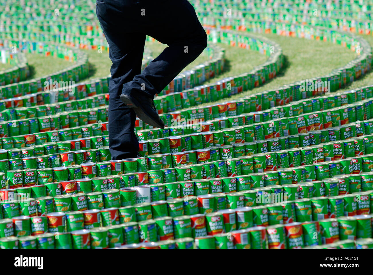 Person stepping between rows of cans of baked beans arranged into a ...