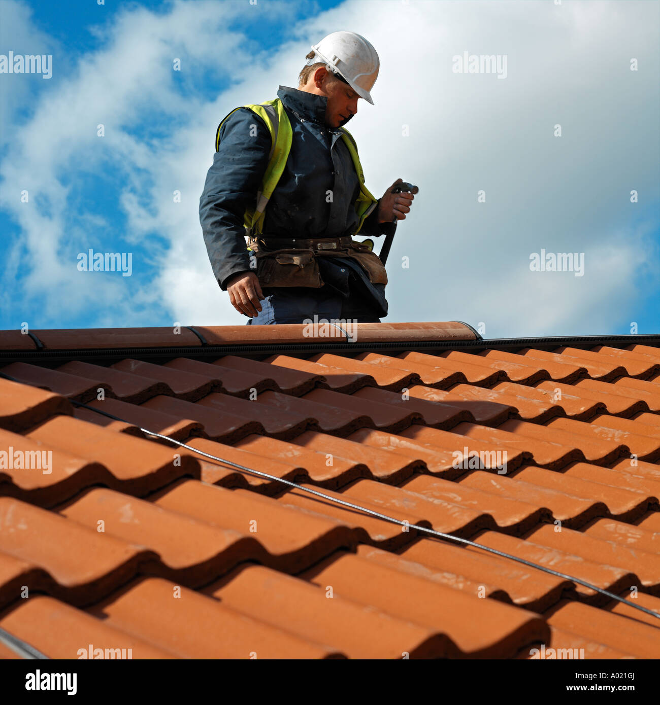 Roof tiler stands against blue sky on a house roof in Newcastle England ...
