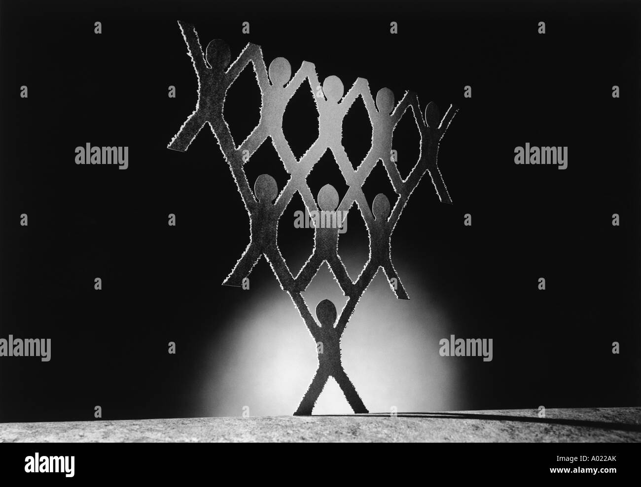Pyramid of cut out paper figures, (b&w Stock Photo - Alamy